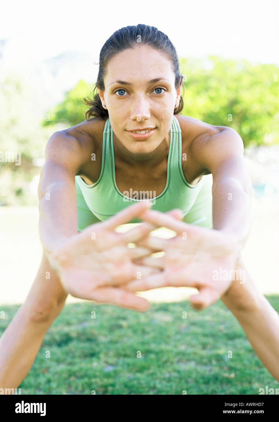 Young woman stretching, looking into camera, hands out toward camera ...
