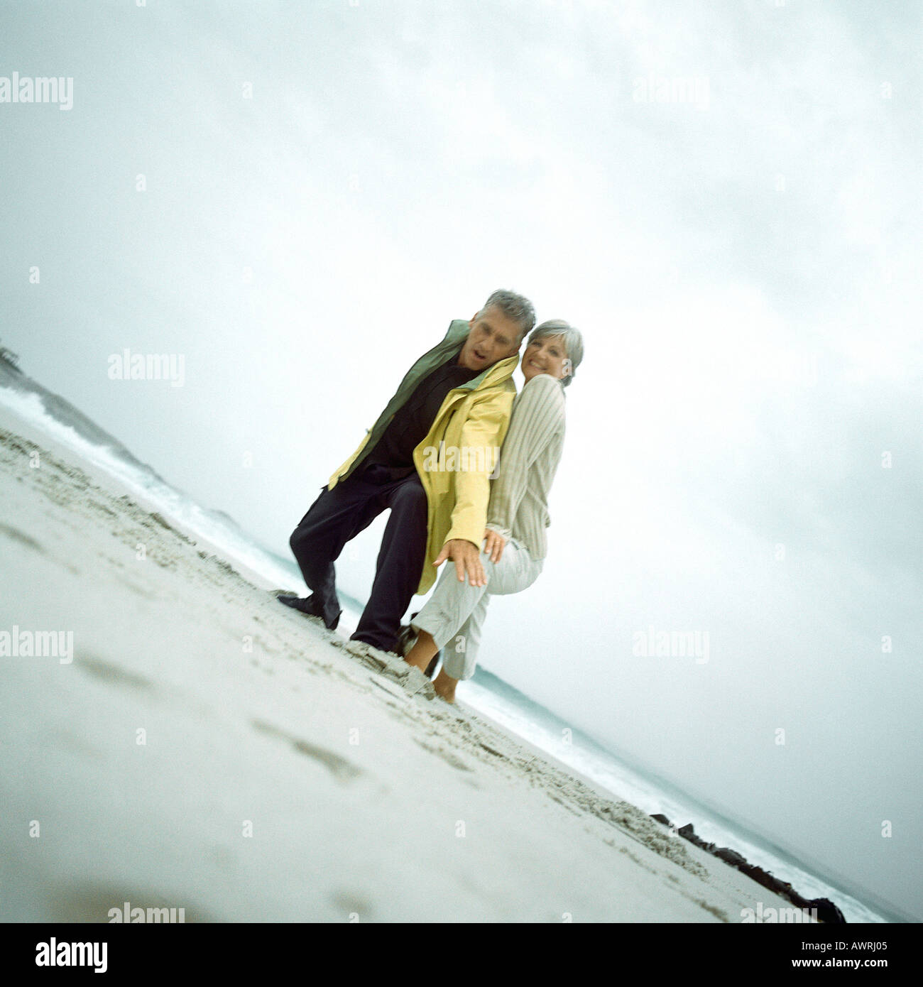Mature couple on beach looking down into camera Stock Photo - Alamy