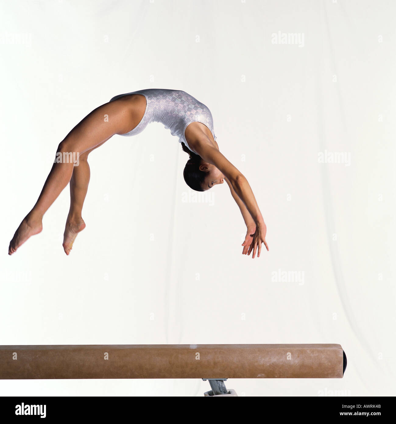 Young female gymnast over balance beam, mid-air, side view Stock Photo ...
