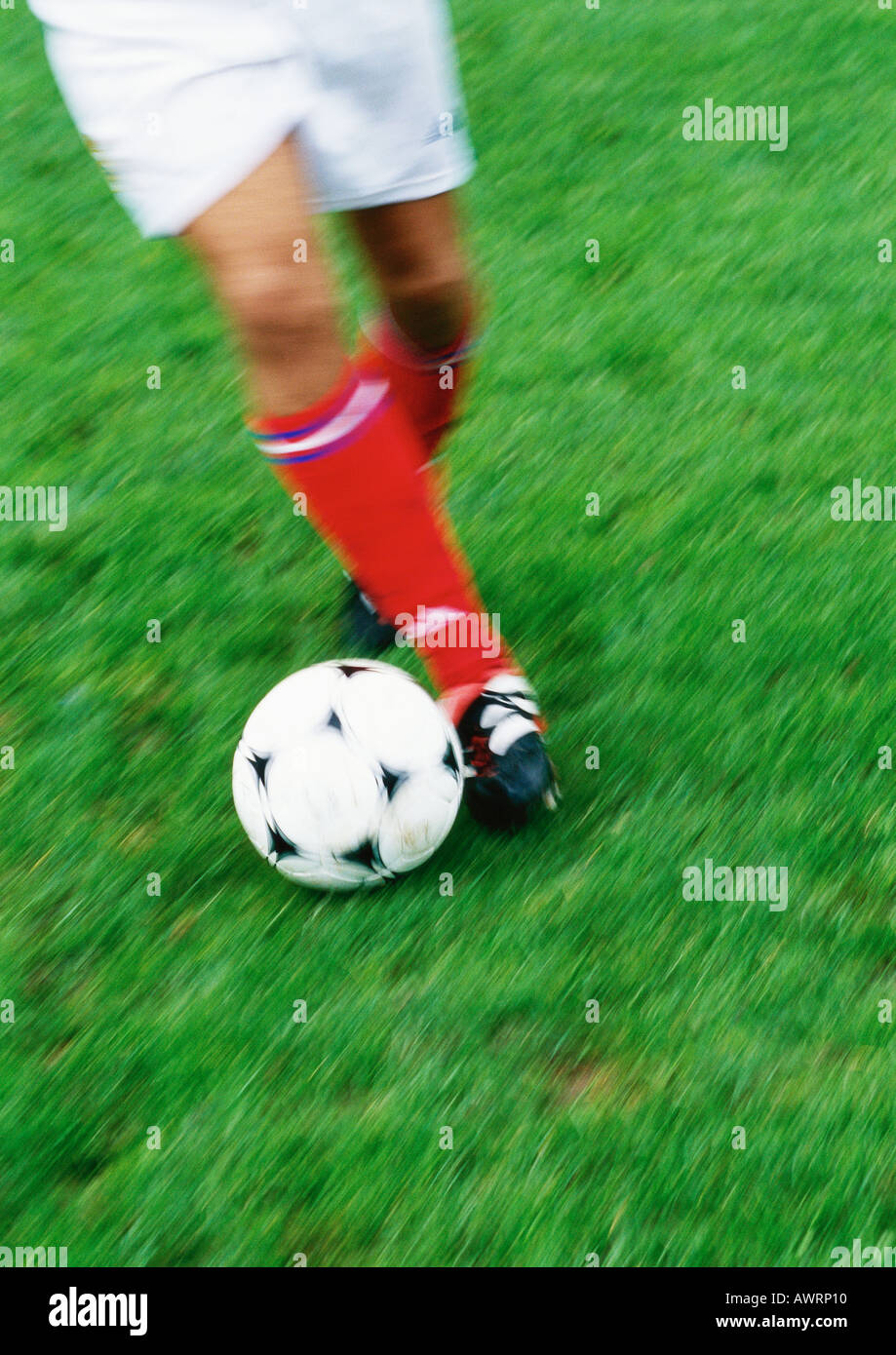 Soccer player running with ball, blurred, low section Stock Photo - Alamy