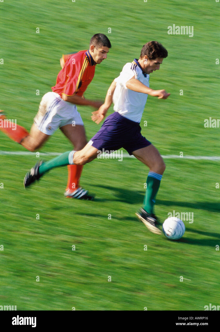 Soccer player running with ball, opponent chasing him, full length ...