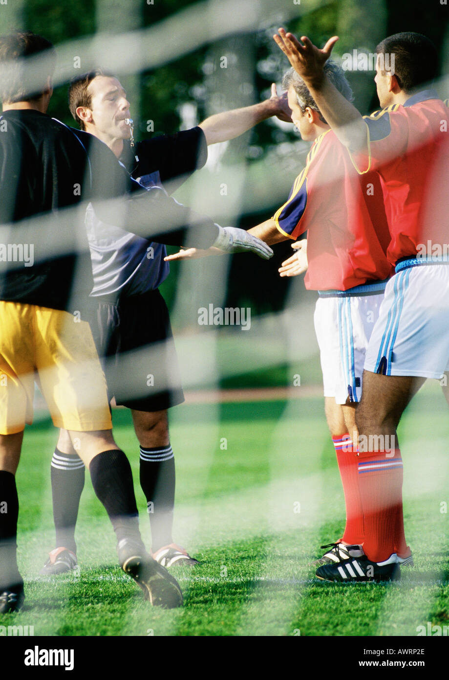 Referee and soccer players during a match, seen from behind the goal ...