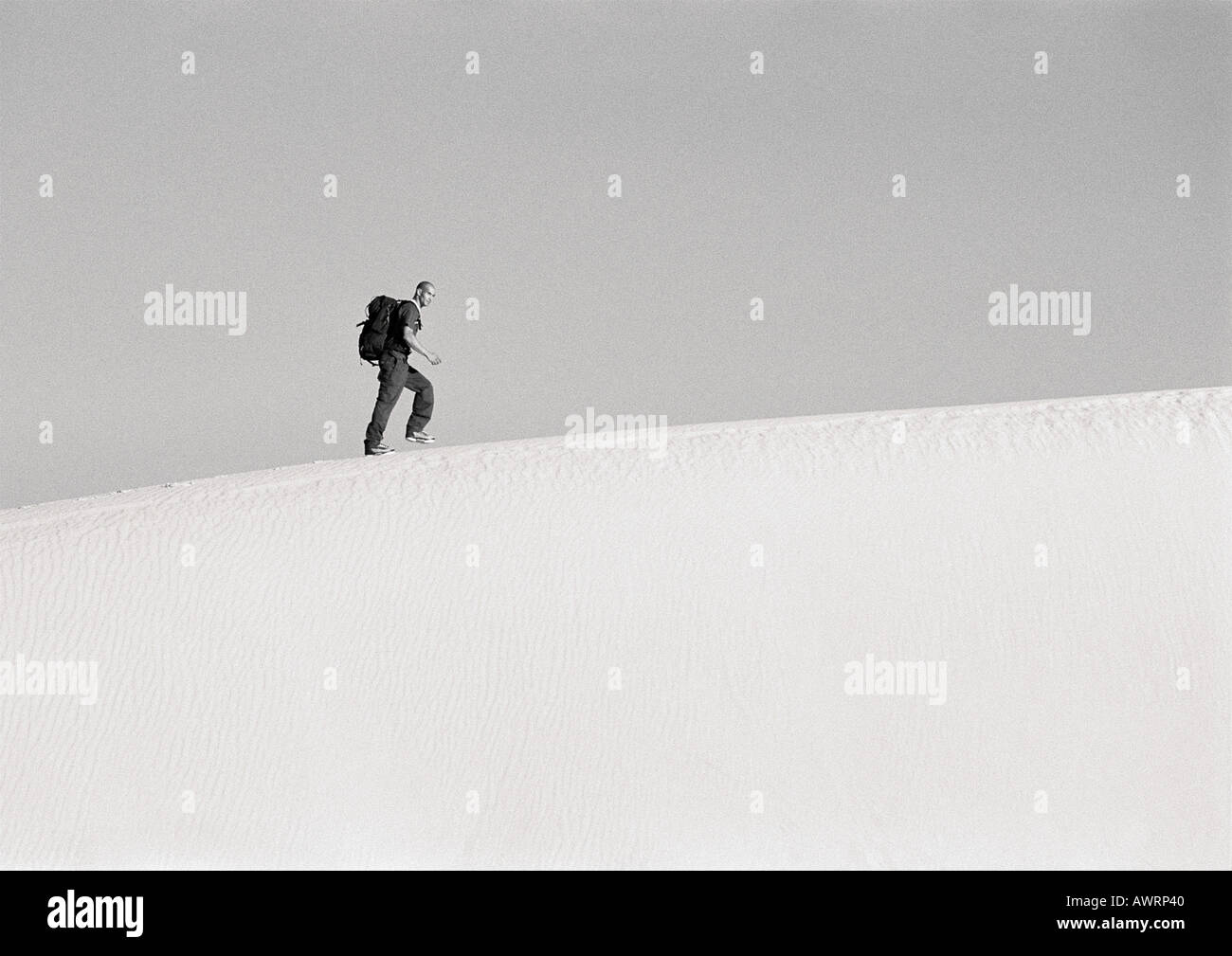 Man hiking along crest of dune, side view, b&w Stock Photo - Alamy