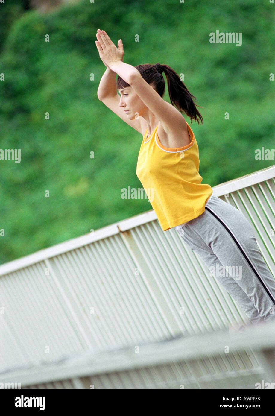 Woman standing on bridge with hands together over head Stock Photo - Alamy
