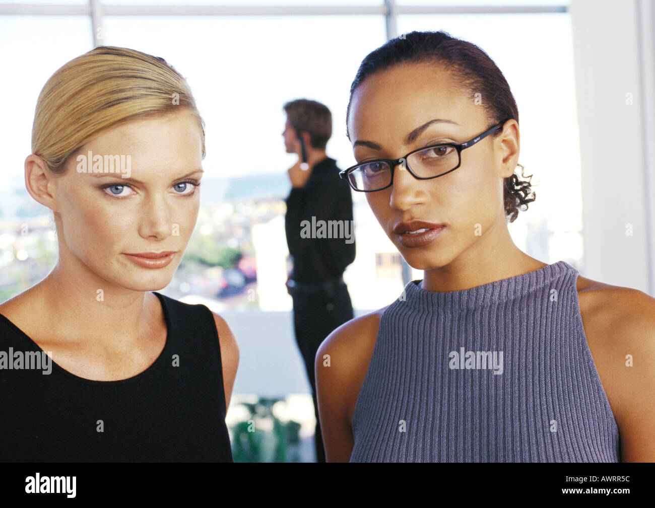 Businesswomen looking into camera, man in background Stock Photo - Alamy