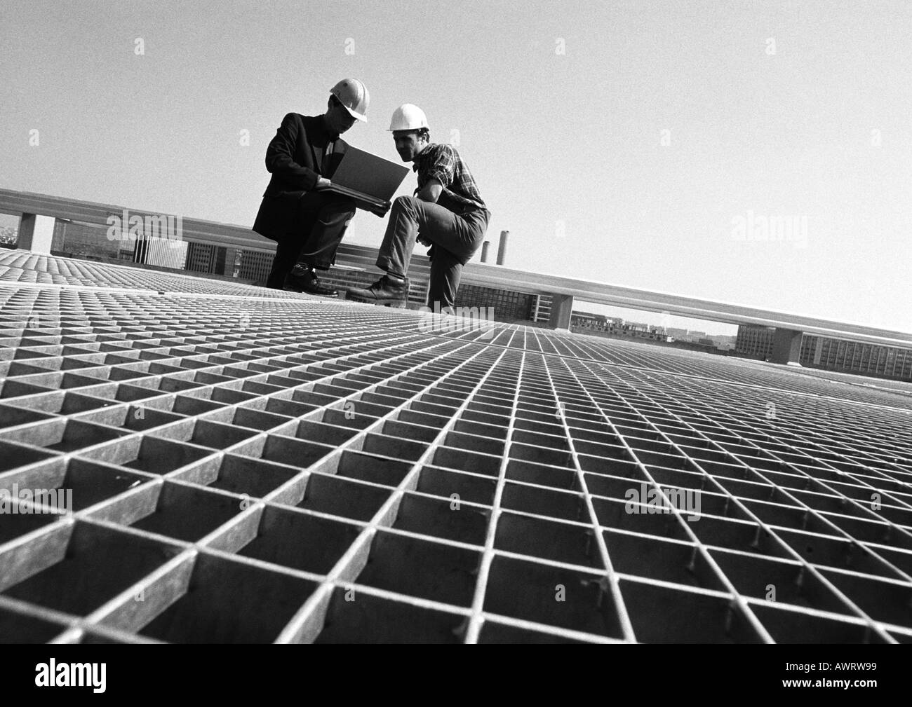 Two men wearing hard hats, looking at laptop computer, b&w Stock Photo ...