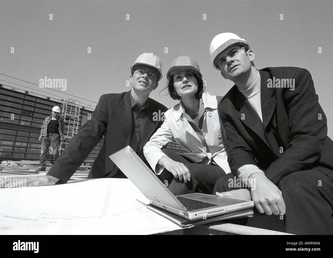 Three people wearing hard hats, one with laptop computer, b&w Stock ...