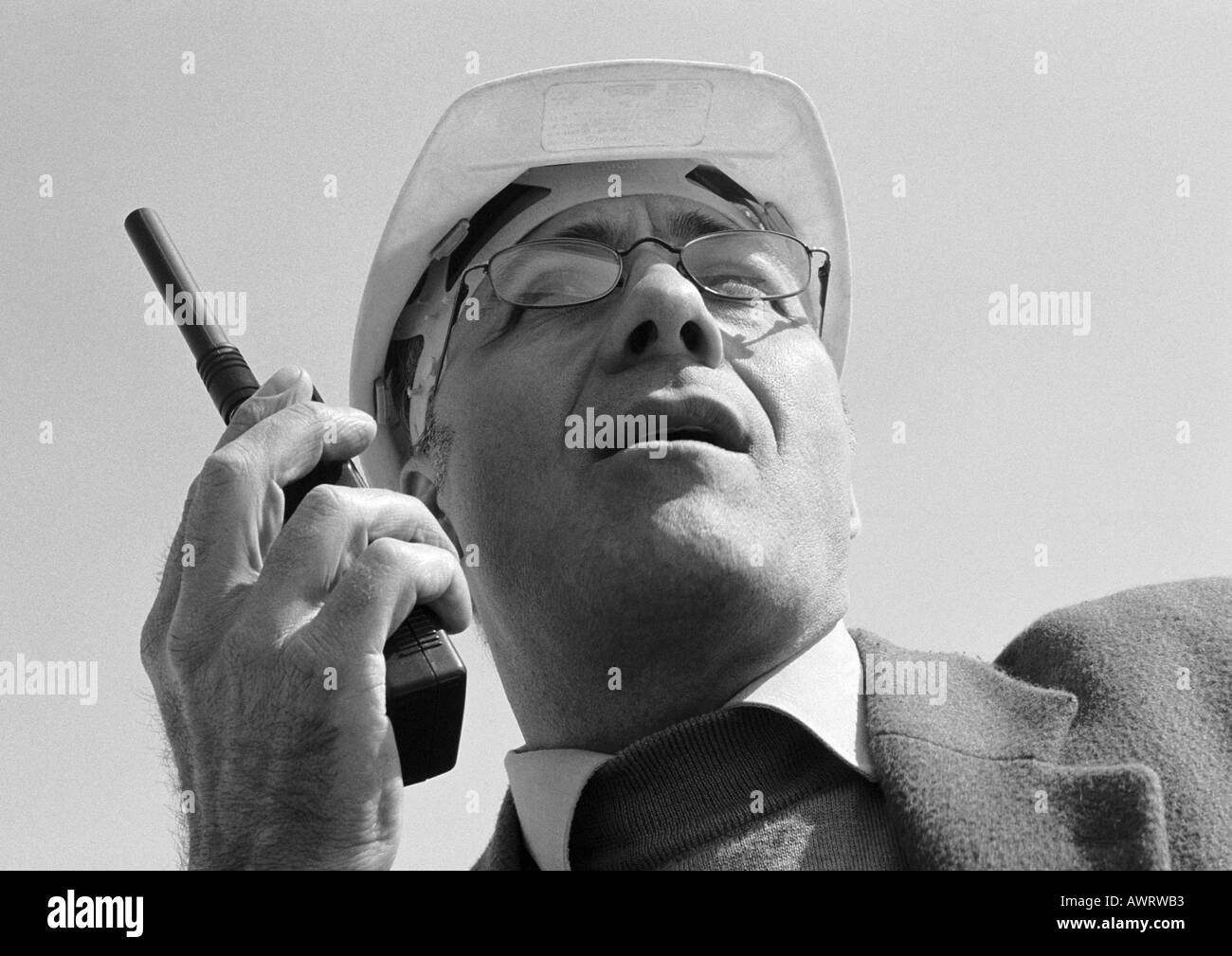 Man with hard hat using walkie-talkie, close-up, low angle view, b&w ...
