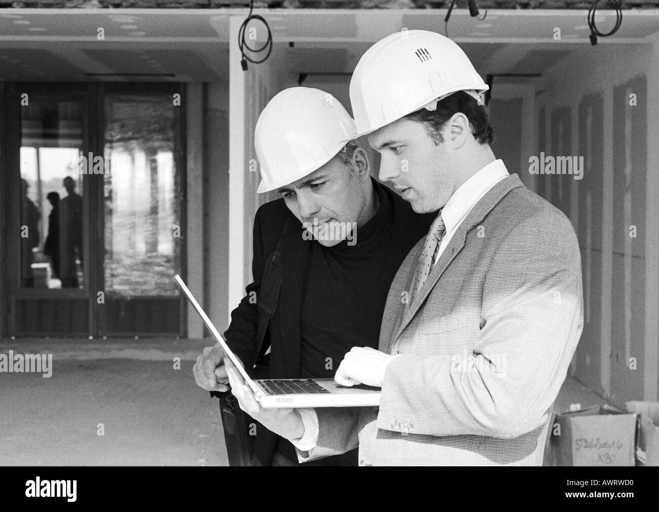Two men with hard hats, one holding laptop computer, b&w Stock Photo ...