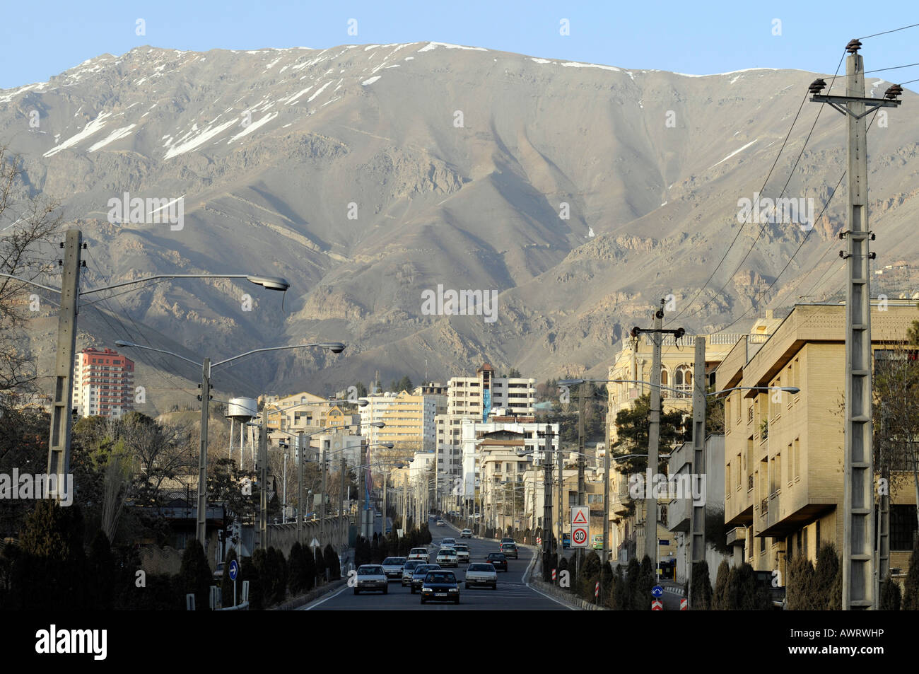A view of North Tehran, with big mountains rising behind buildings and ...