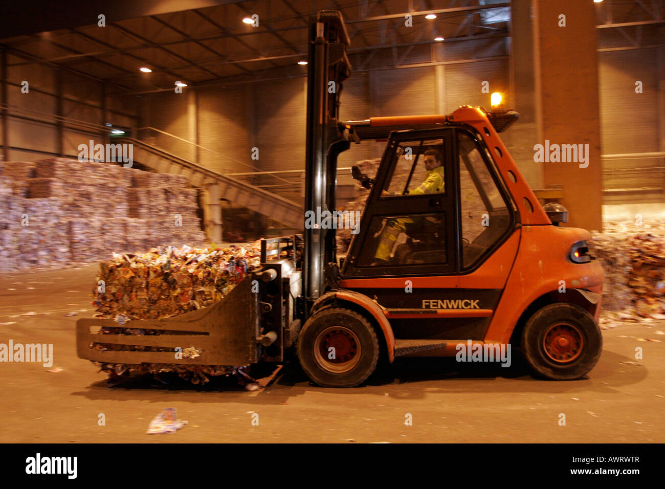 Forklift carrying waste paper bales to be recycled for paper production ...