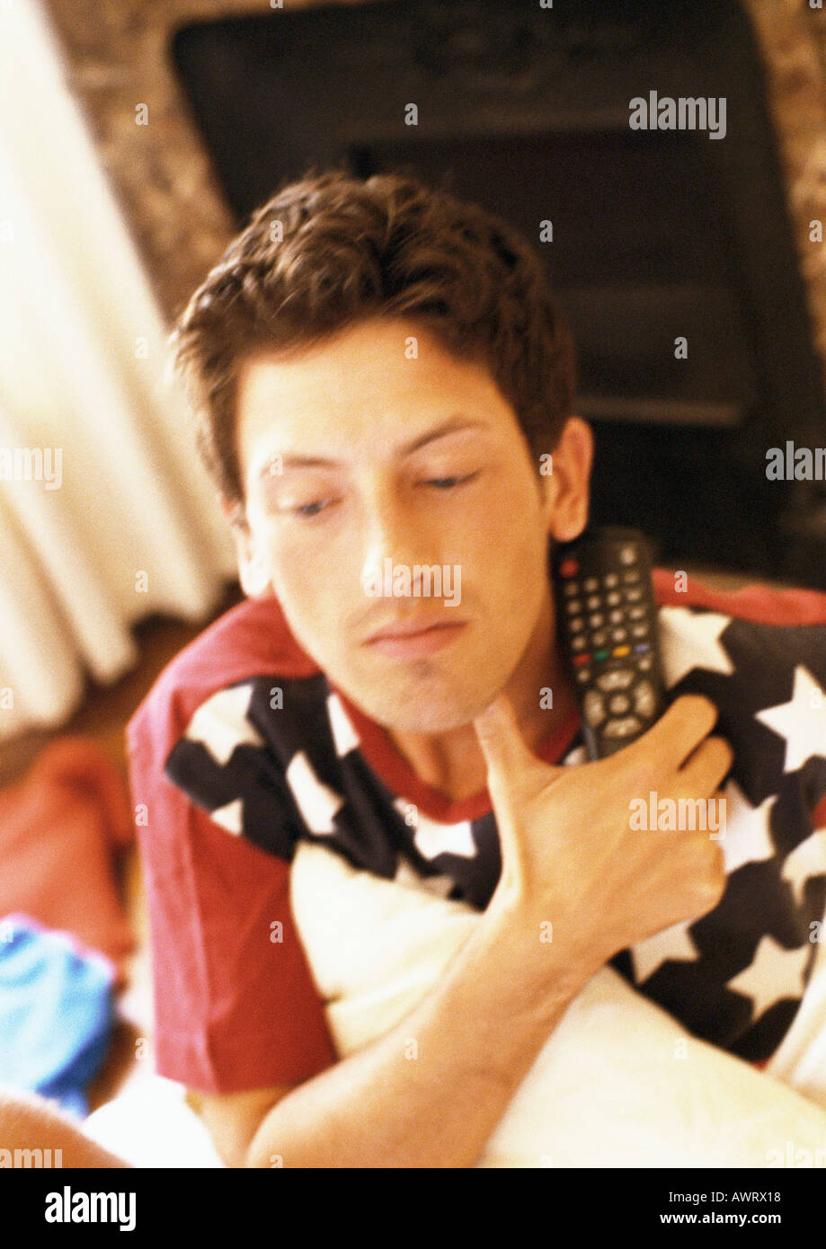 Man holding remote control in hand and pillow under arm Stock Photo - Alamy