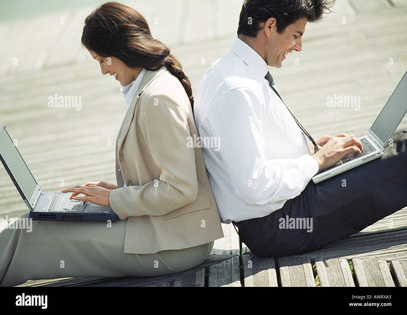 Businessman and woman back to back on ground with laptop computers on ...