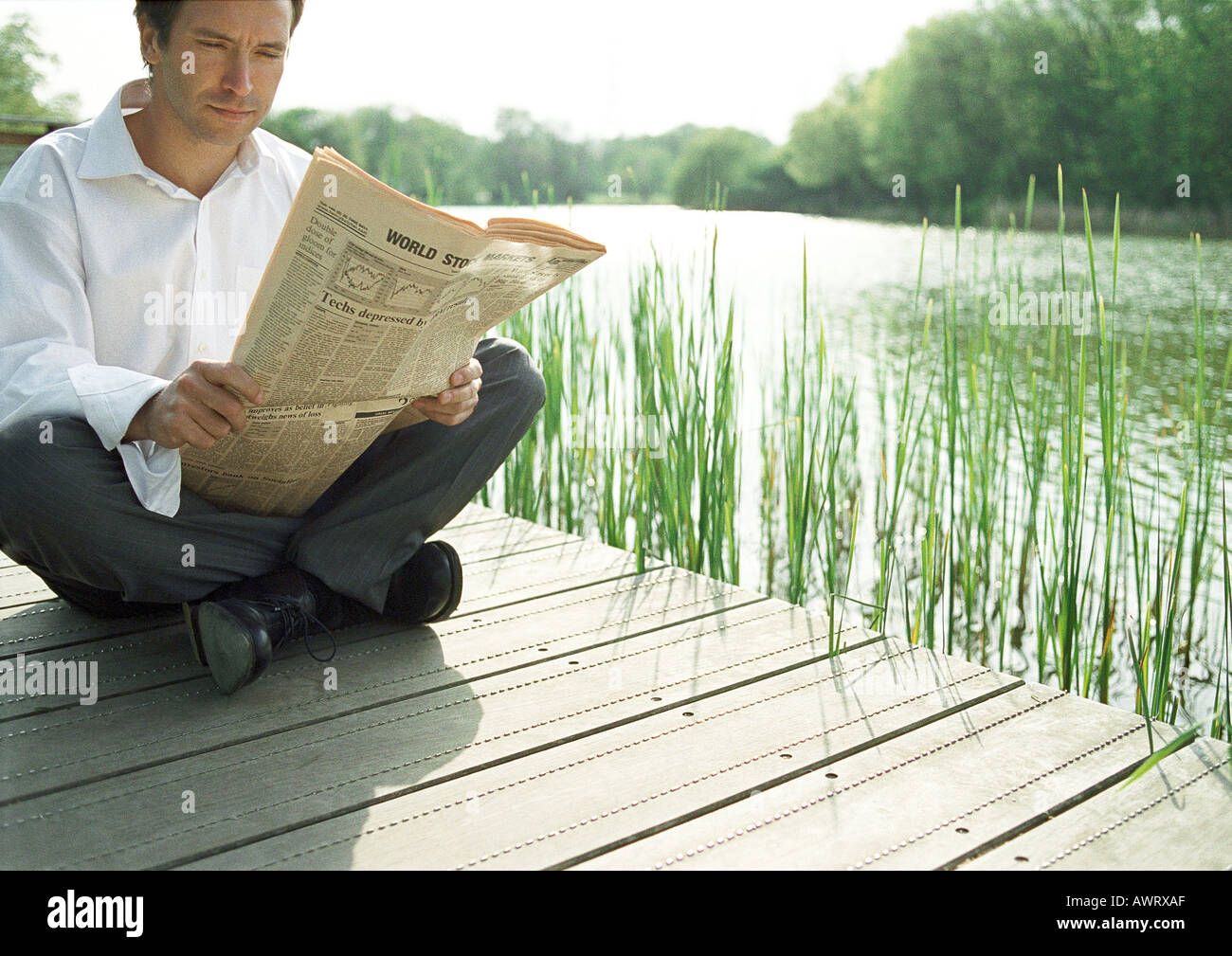 Man sitting outdoors, reading newspaper Stock Photo - Alamy
