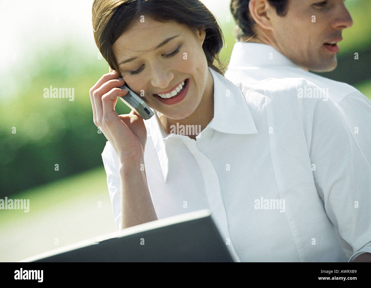 Businessman and woman back to back, woman using cell phone, head and ...