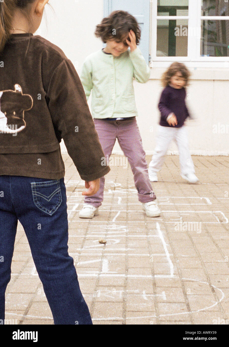 Three children playing hopscotch Stock Photo - Alamy