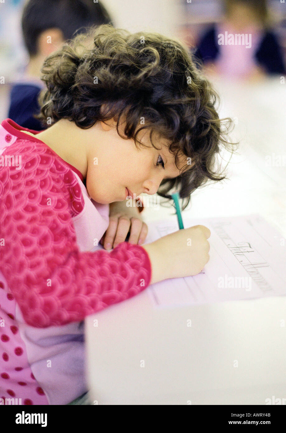 Child in classroom, writing, side view Stock Photo - Alamy