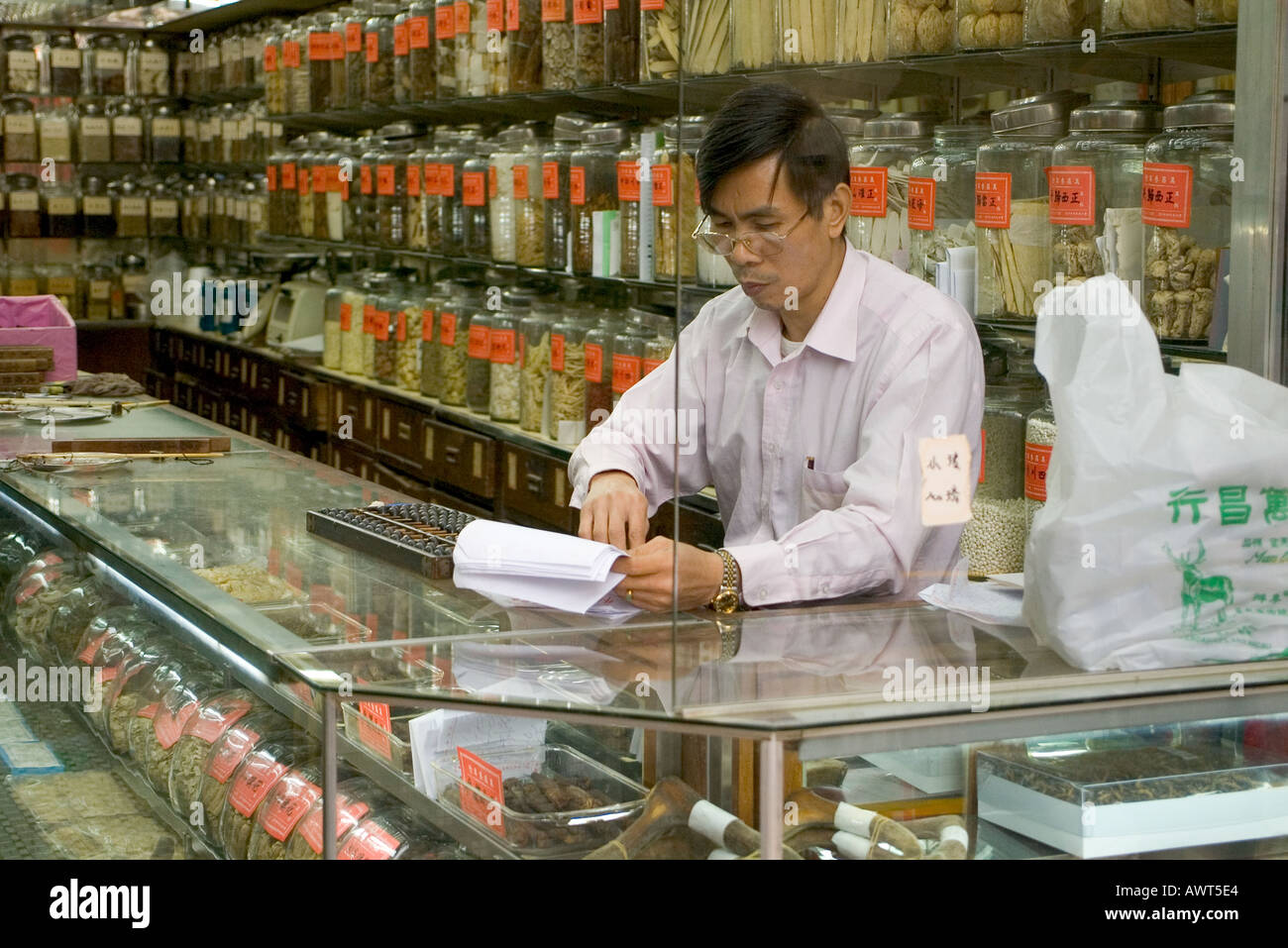dh MACAU CHINA A Chinese man counting using abacus in medicine shop ...