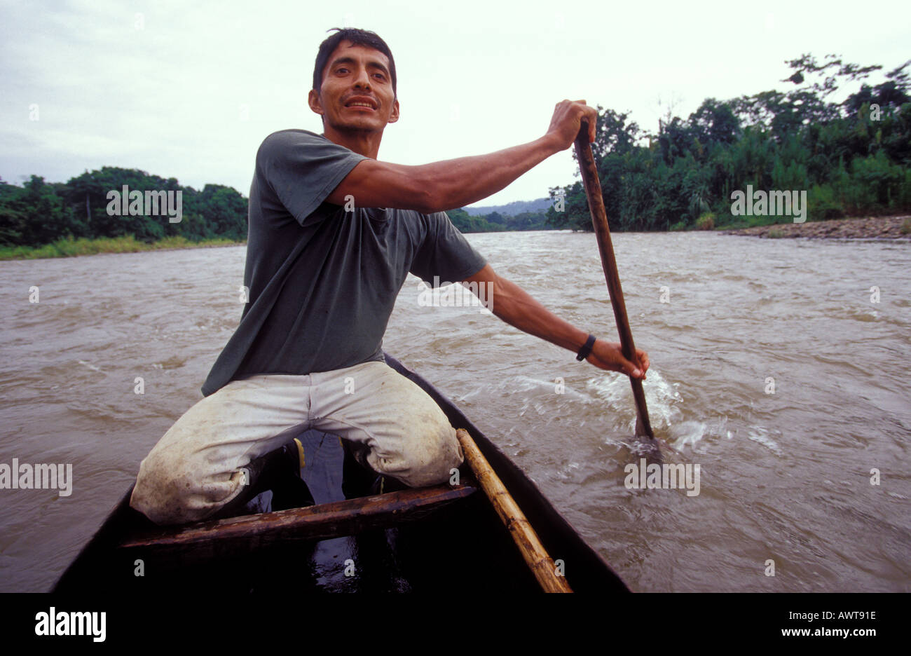 native man rowing a canoe in a river at the Oriente jungle area near ...