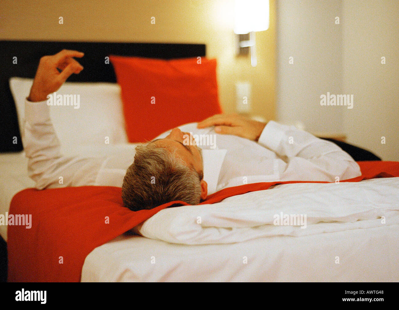 Businessman lying across bed Stock Photo - Alamy