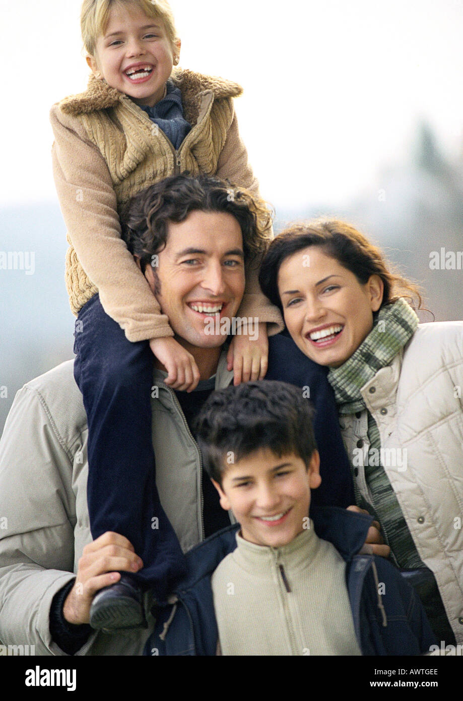 Adult man and woman standing with two children, little girl on man's ...