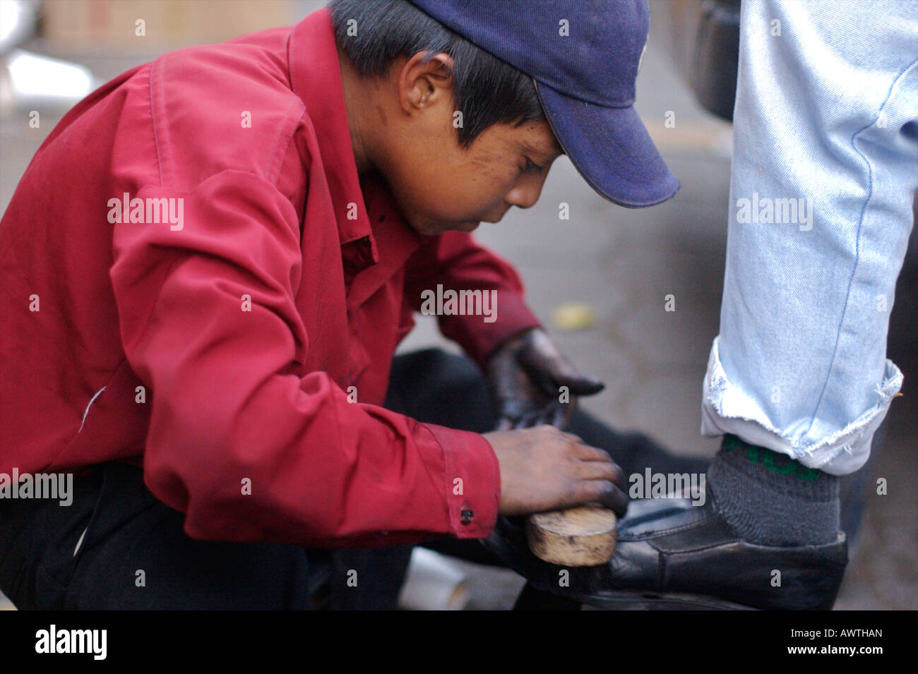 A shoe shine boy polishes a shoe near the central market in Antigua ...