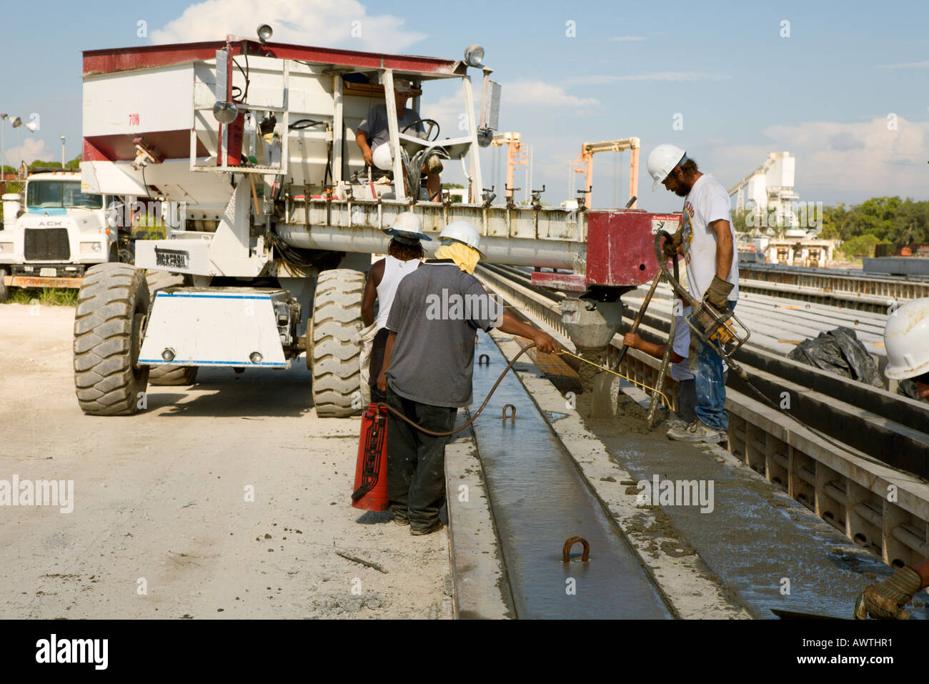 Workers pour concrete into forms to make prestressed concrete piling ...