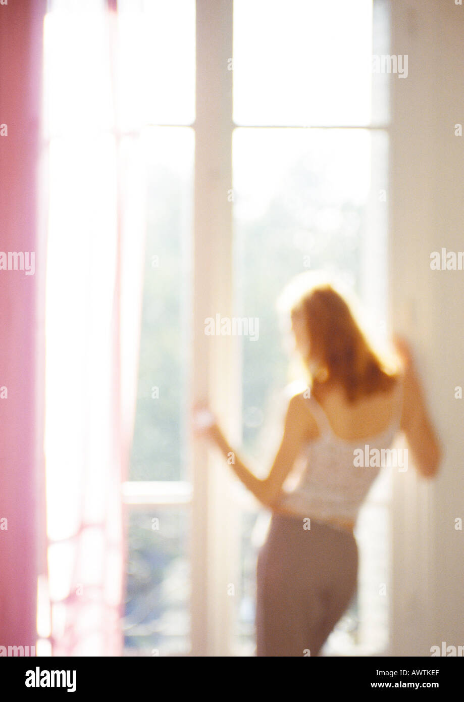 Woman looking out of window, rear view, three quarter length, blurred ...