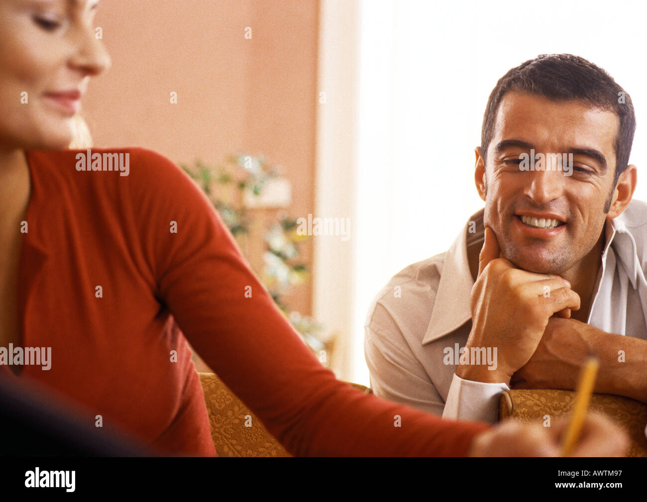Man smiling, watching woman write Stock Photo - Alamy
