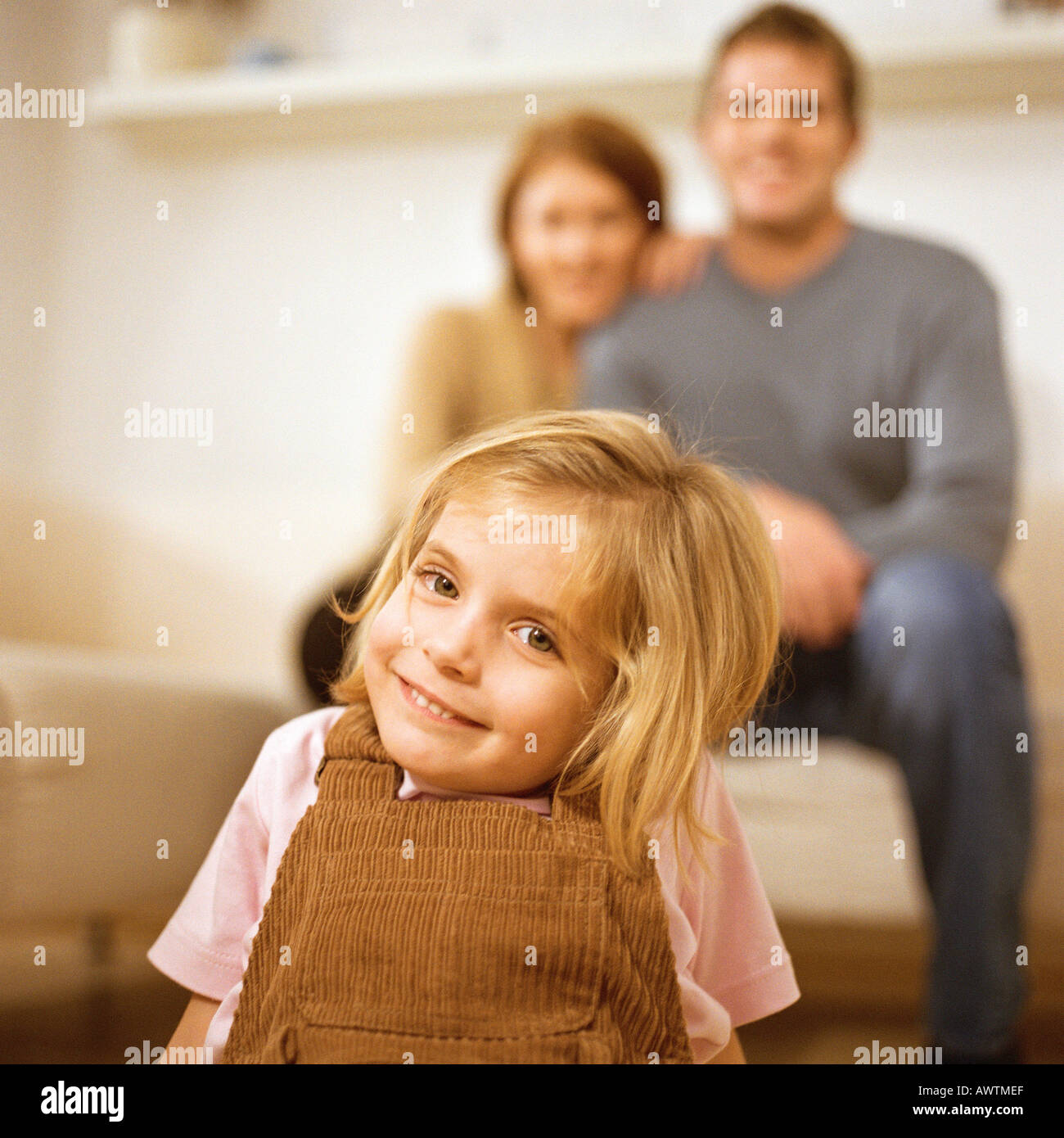 Little girl smiling at camera, parents behind her Stock Photo - Alamy