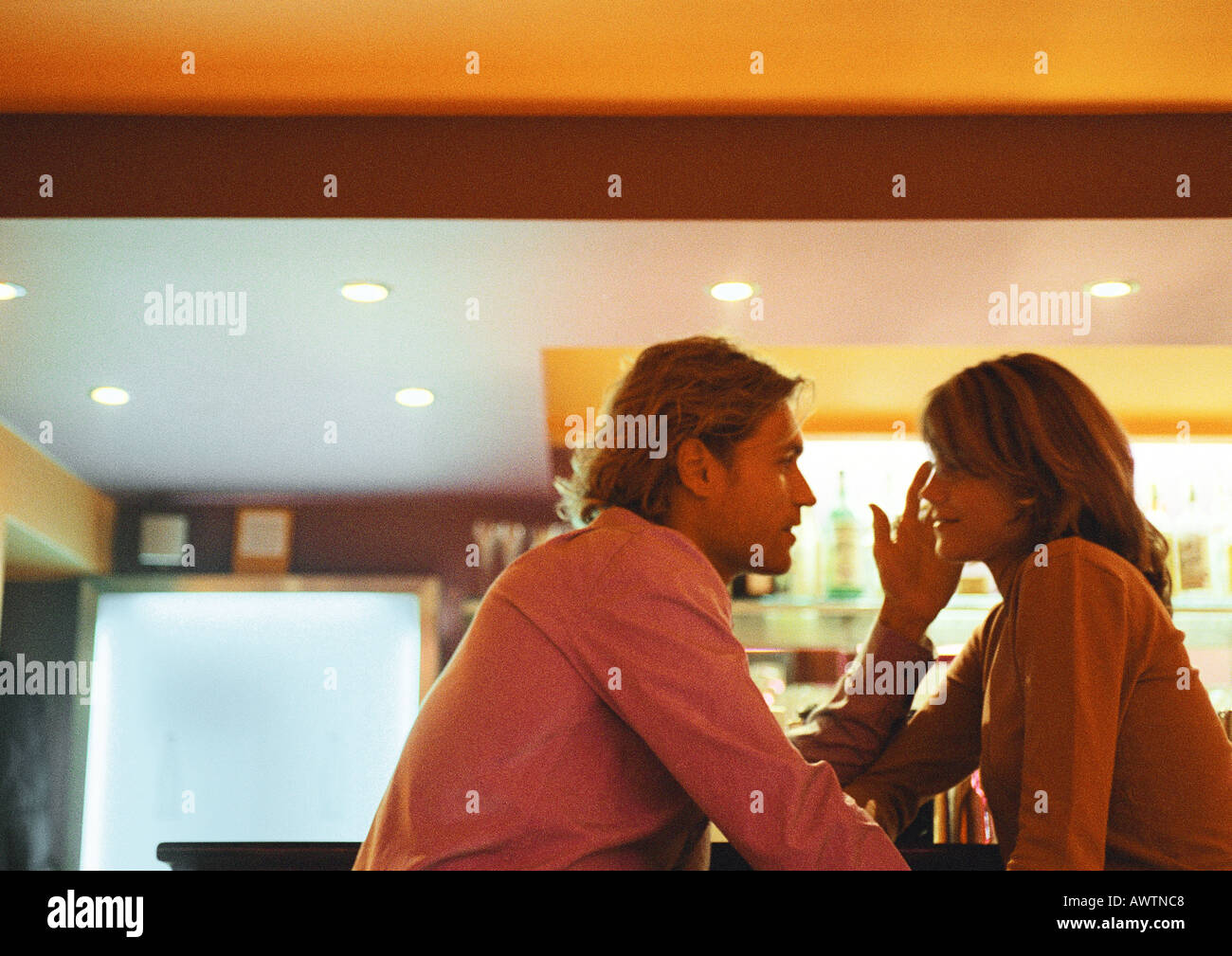 Couple sitting face to face, man touching woman's face Stock Photo - Alamy