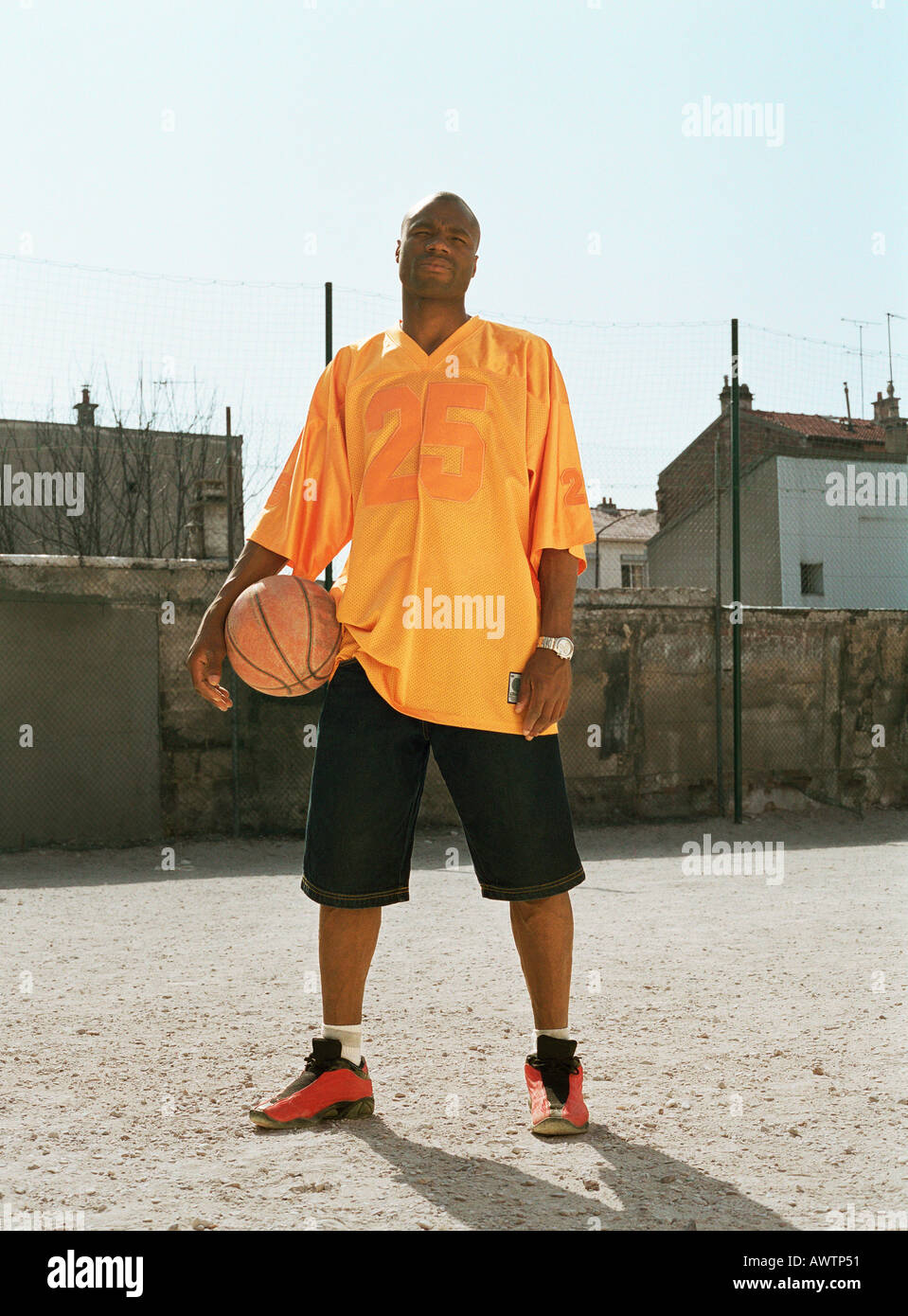 Man standing with a basketball in urban playground Stock Photo - Alamy