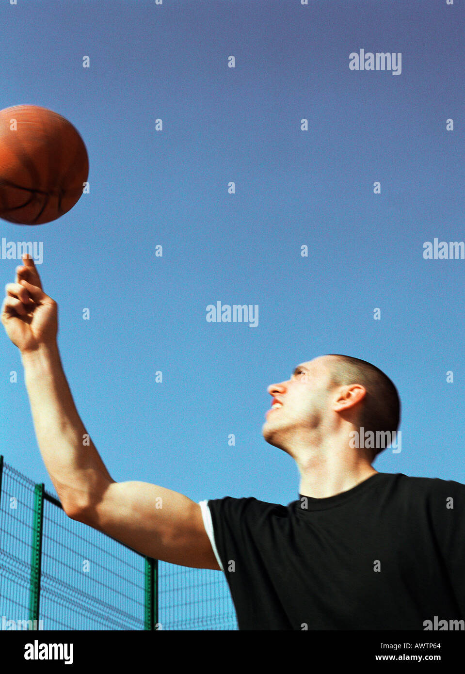 Man looking up at spinning basketball Stock Photo - Alamy