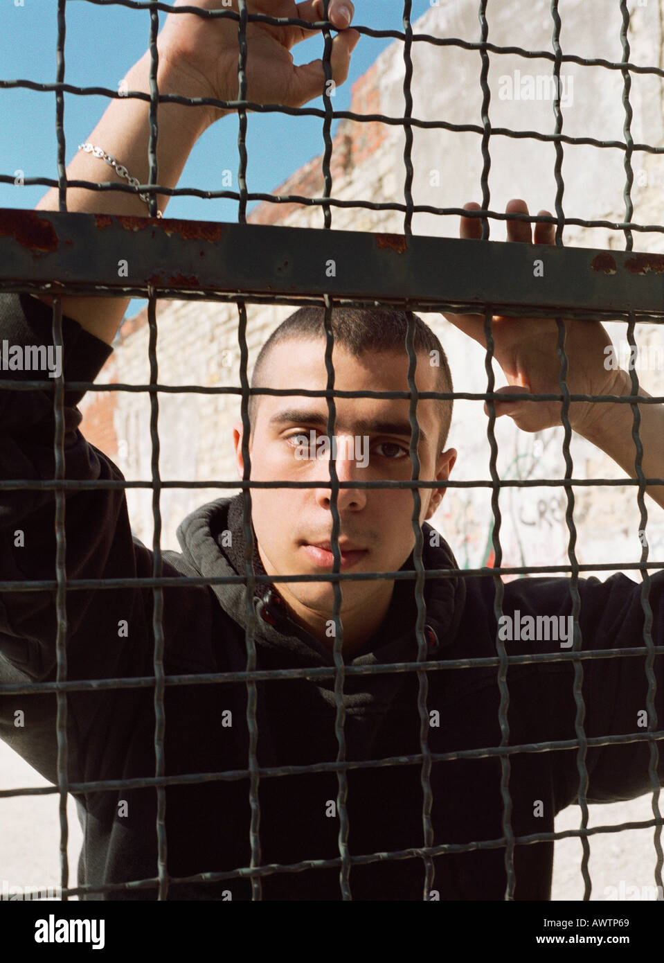 Man standing behind fence, looking at camera, portrait Stock Photo - Alamy