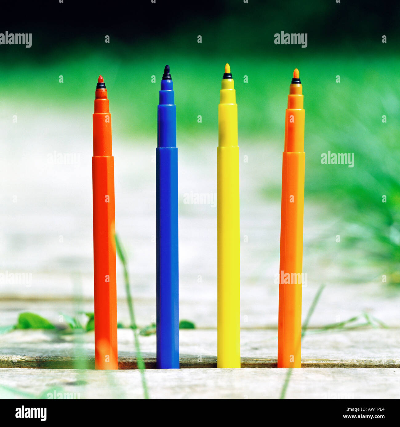 Colored felt-tip pens standing up from between planks of wooden walkway ...