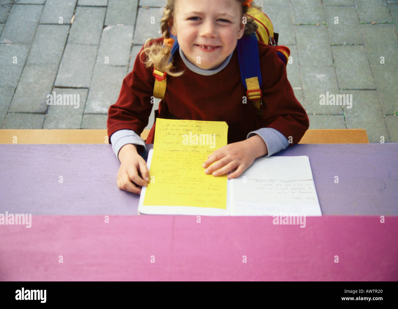 Little girl holding paper, looking up at camera Stock Photo - Alamy