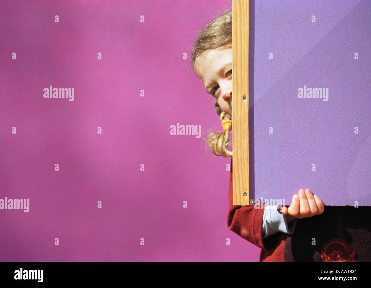 Little girl peeking around corner Stock Photo - Alamy