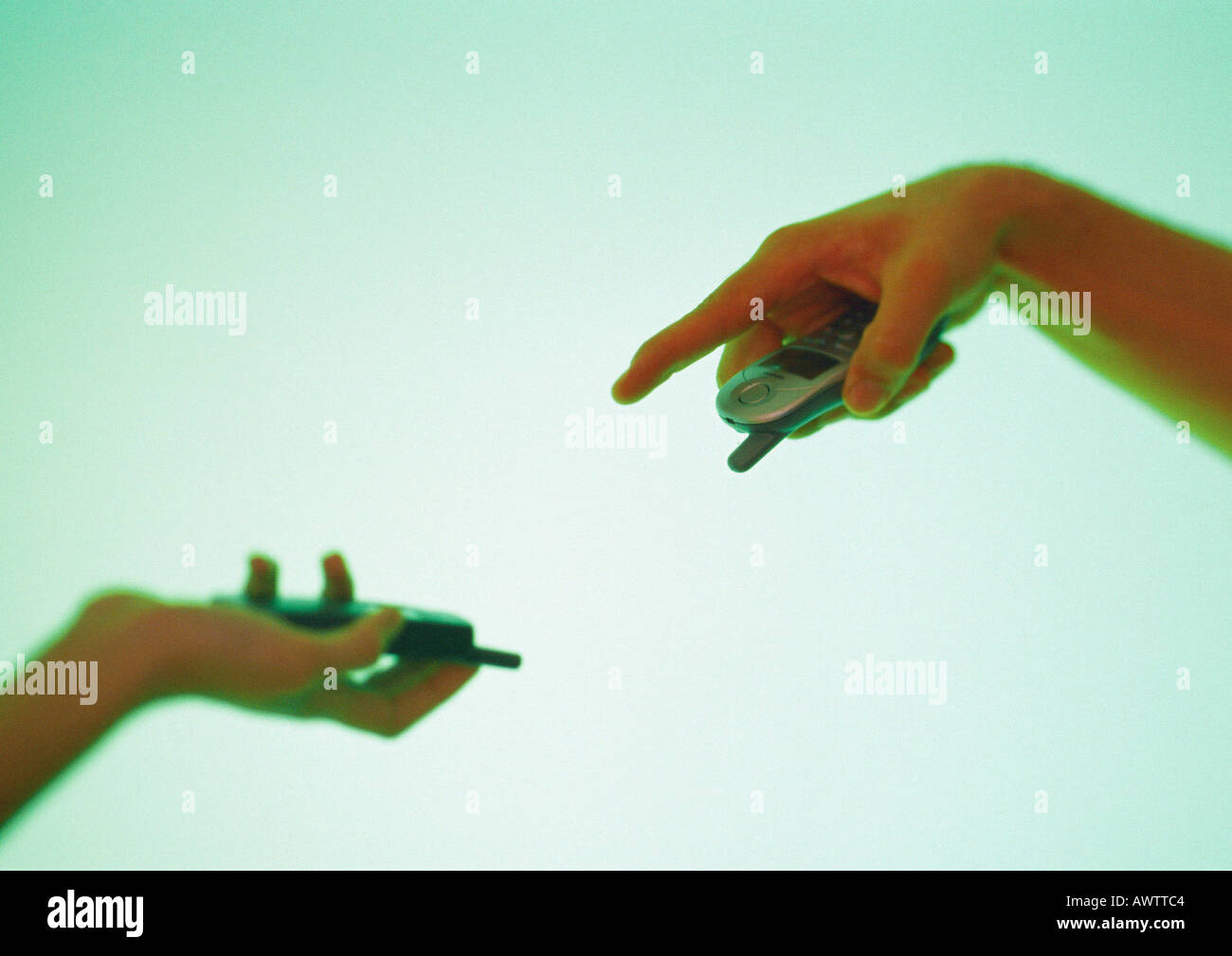 Two hands holding cell phones, one gesturing to other Stock Photo - Alamy