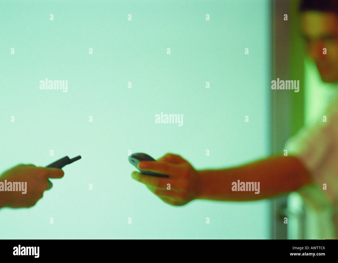 Two people connecting their cellphones using infrared, exchanging data ...