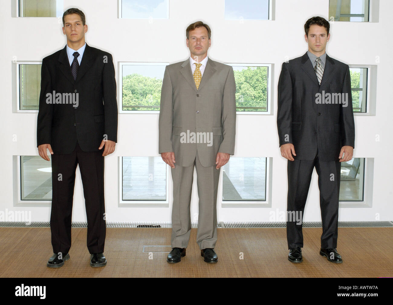 Three businessmen standing in a line Stock Photo - Alamy