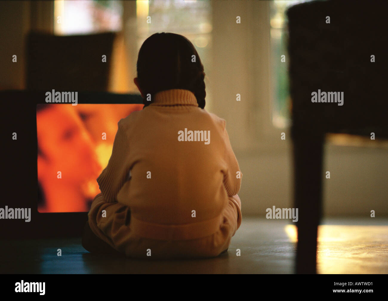 Young girl sitting on floor watching TV, rear view Stock Photo - Alamy