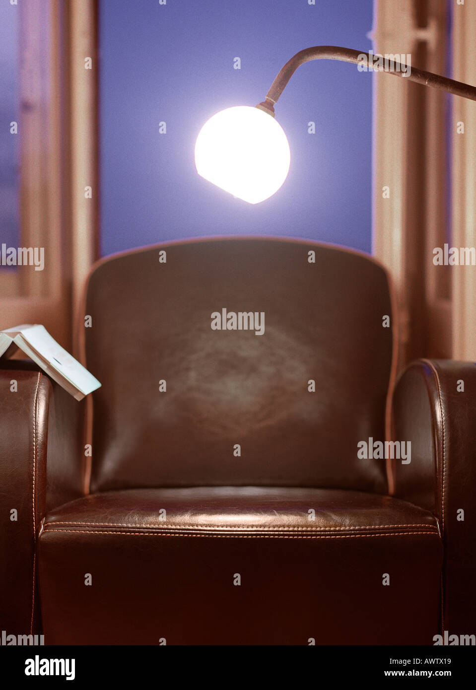 Light shining over chair with open book on arm Stock Photo - Alamy