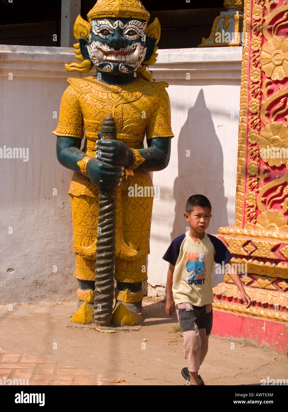 boy walking in front of temple statue in Vientiane Laos Stock Photo - Alamy