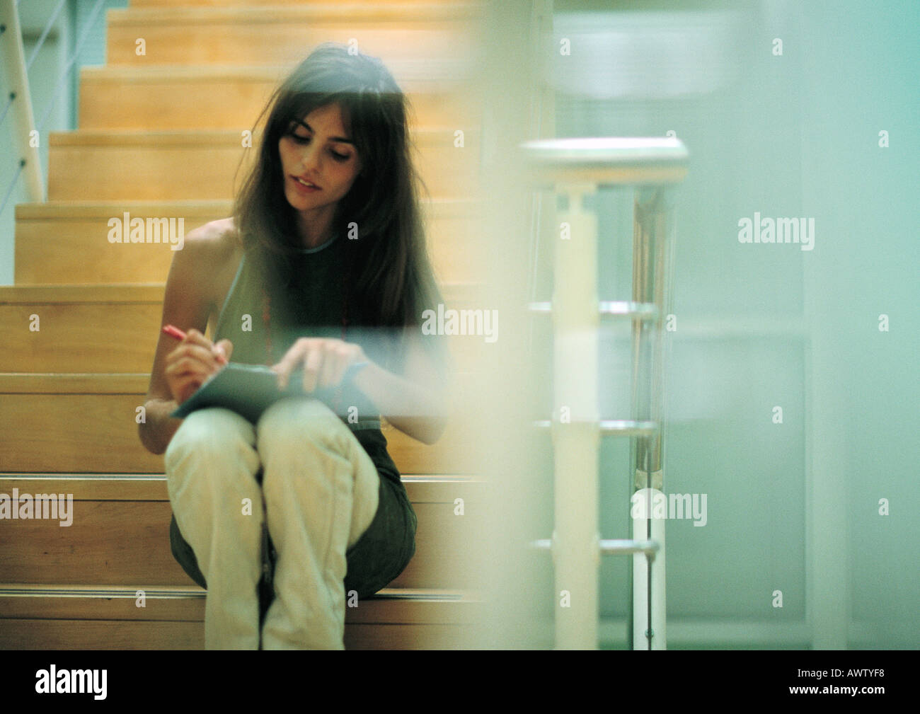 Woman sitting on stairs writing Stock Photo - Alamy