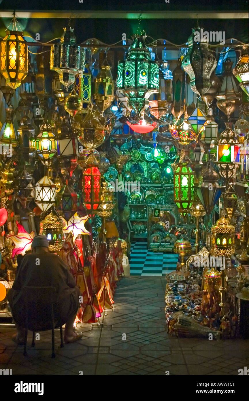 Vertical close up of a shopkeeper sitting outside his colourful shops ...
