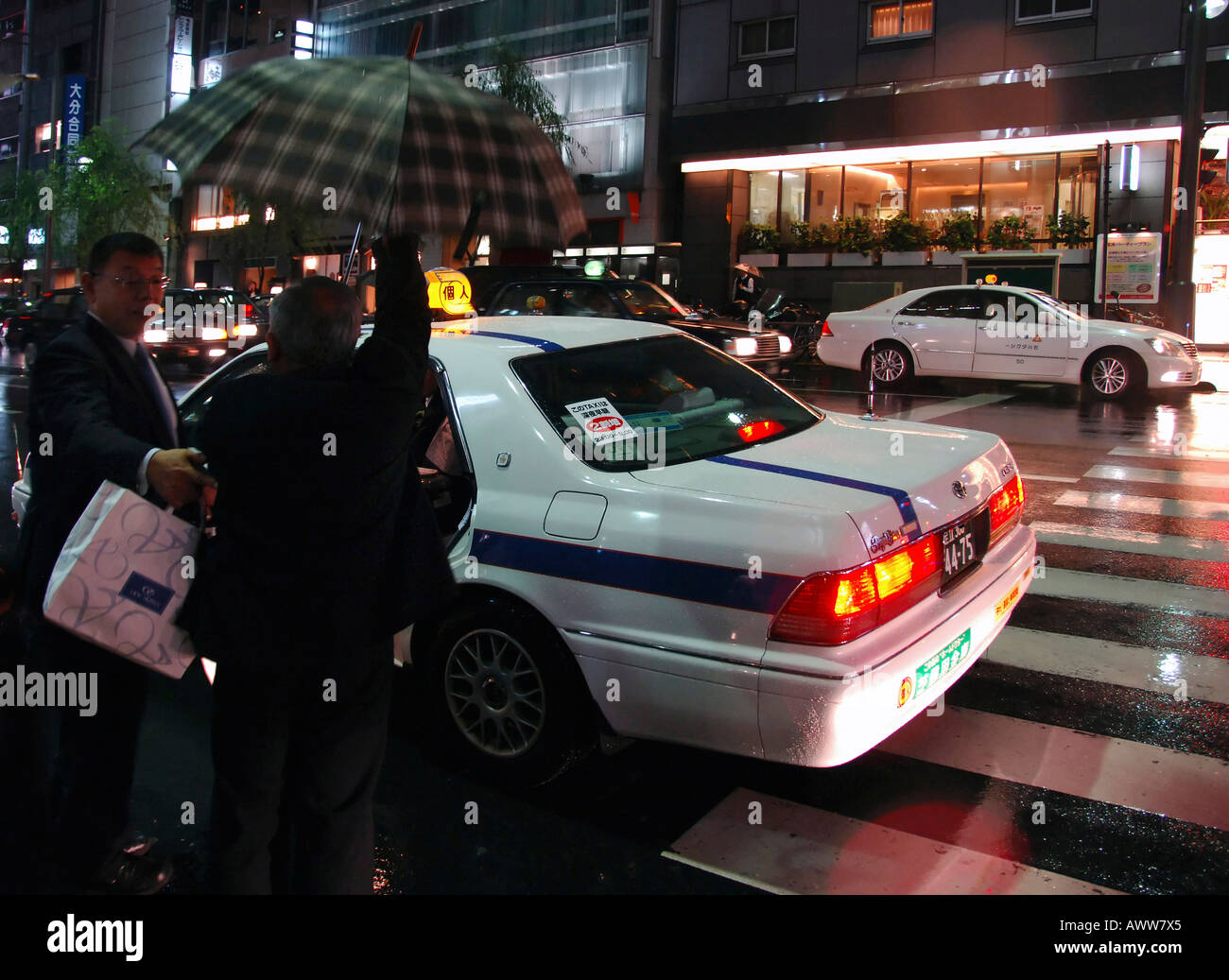 Late night people catching a taxi cab on a rainy Tokyo Street with ...