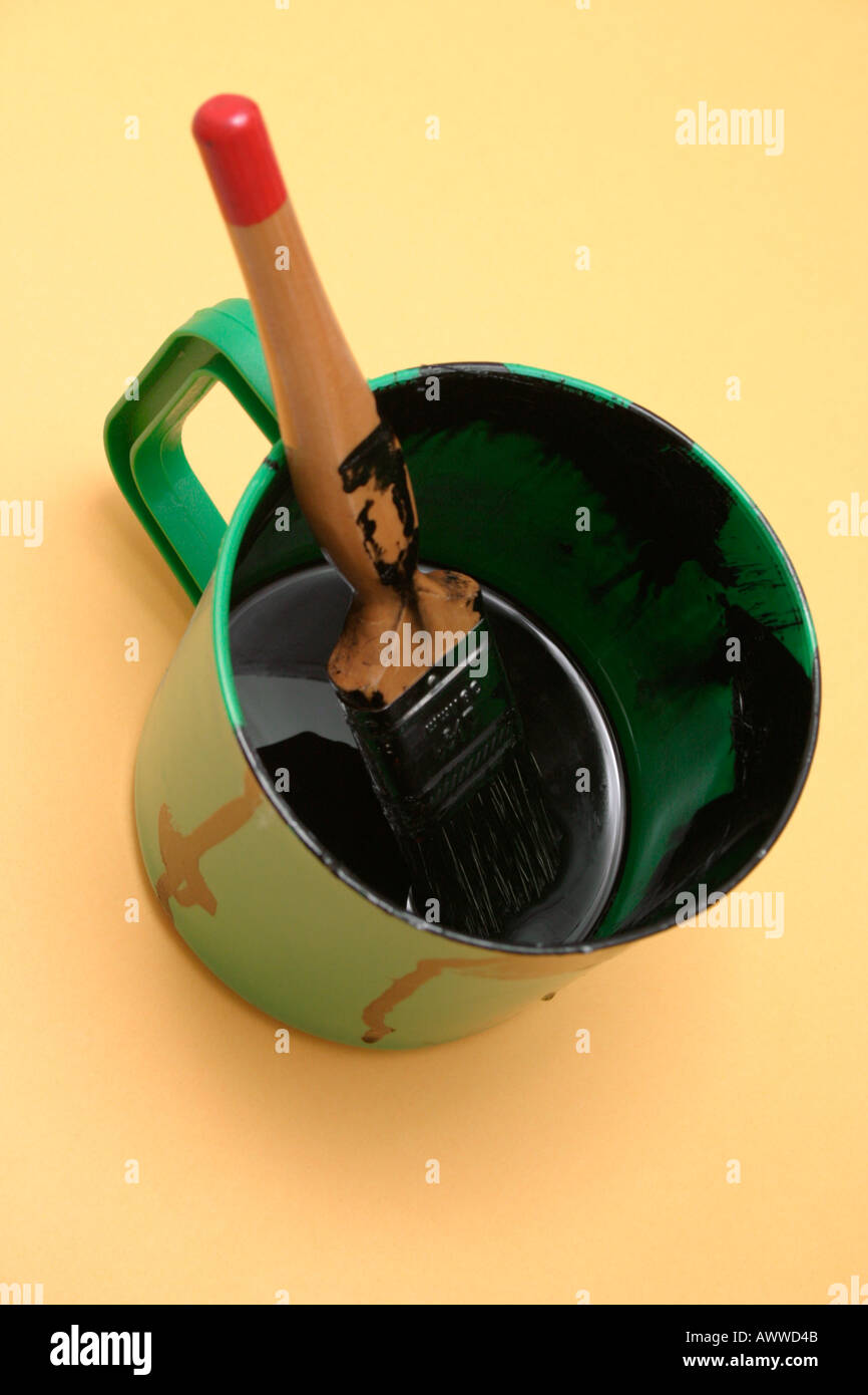 paintbrush in green plastic bucket with turpentine on yellow background ...