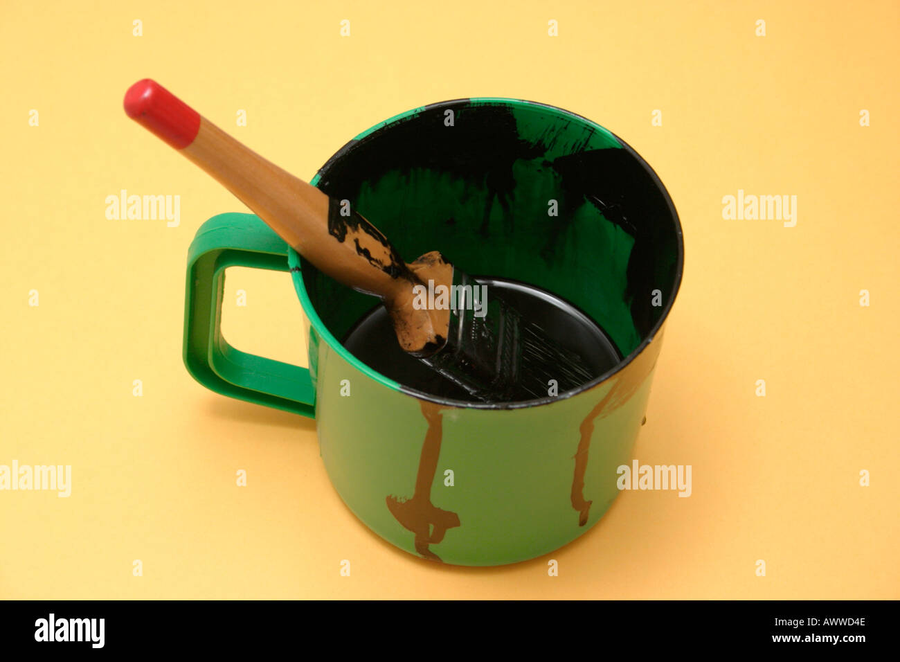 paintbrush in green plastic bucket with turpentine on yellow background ...