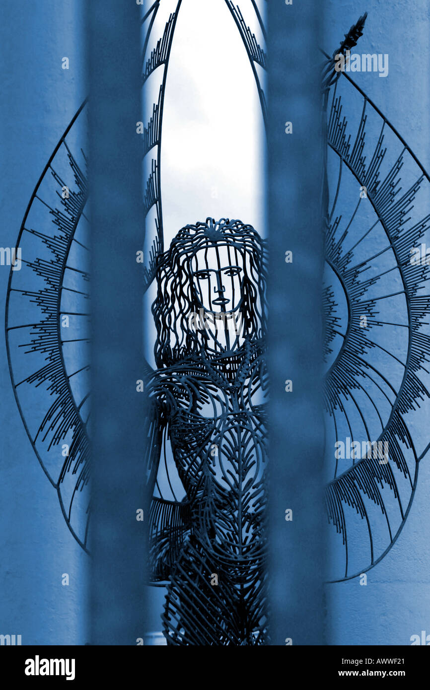 Angel sculpture made from steel rod viewed through bars of security ...