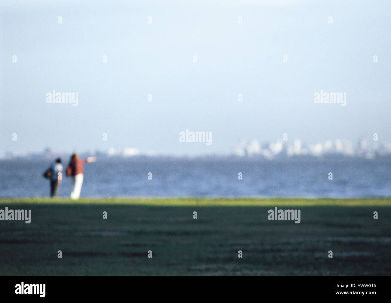 Two people standing together by ocean, blurred Stock Photo - Alamy